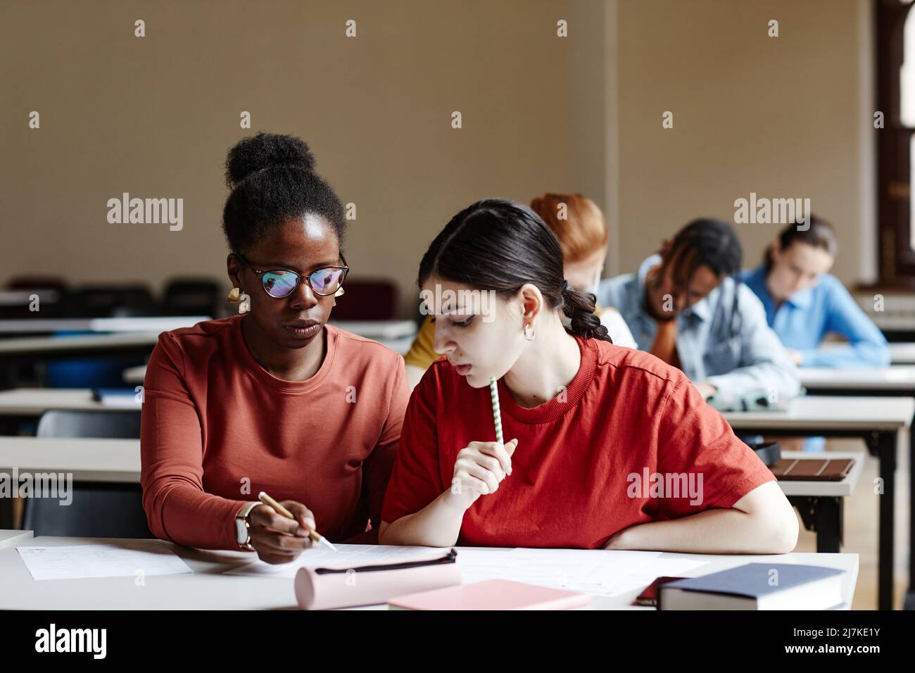 Front view portrait of two young women taking notes while studying in ...