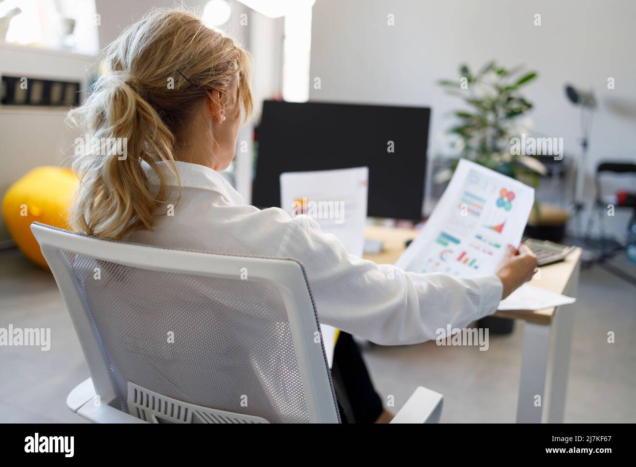 Rear view of a business woman who is examining financial documents with ...