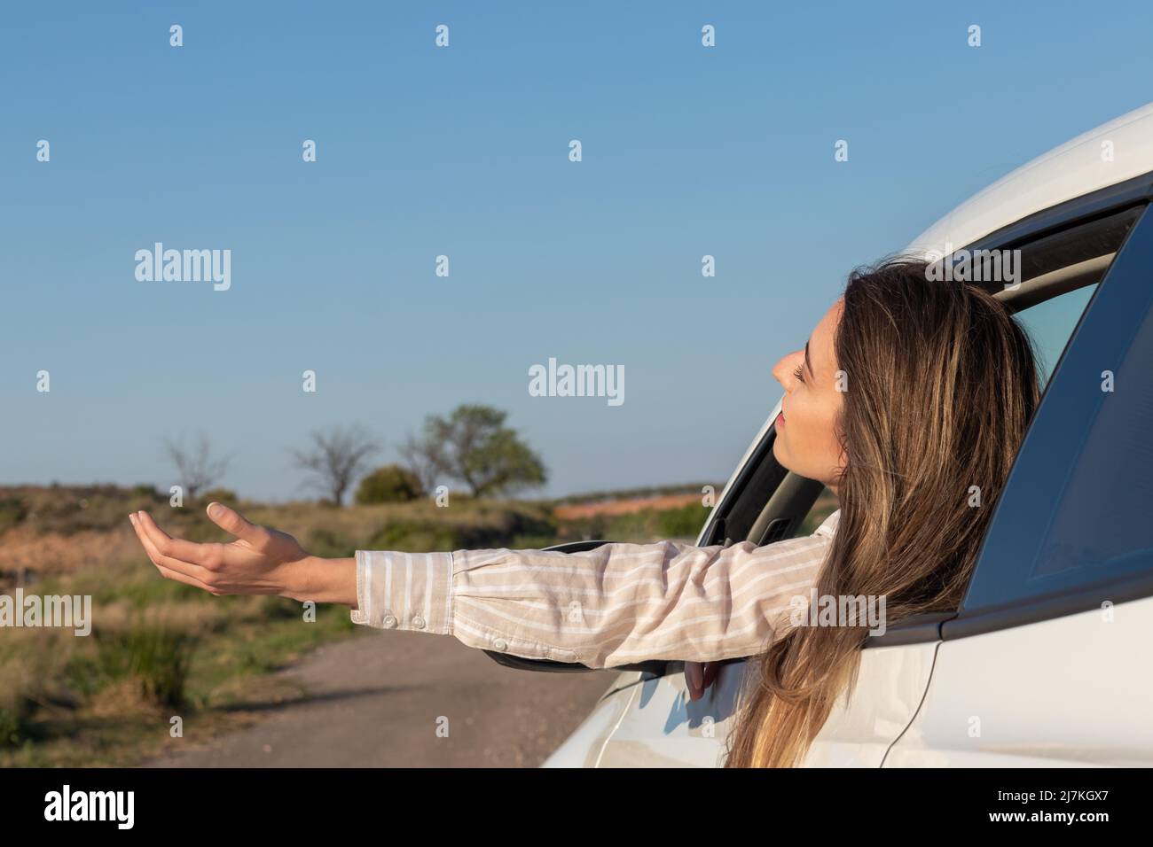 Excited young beautiful woman looking out the car window feeling the ...