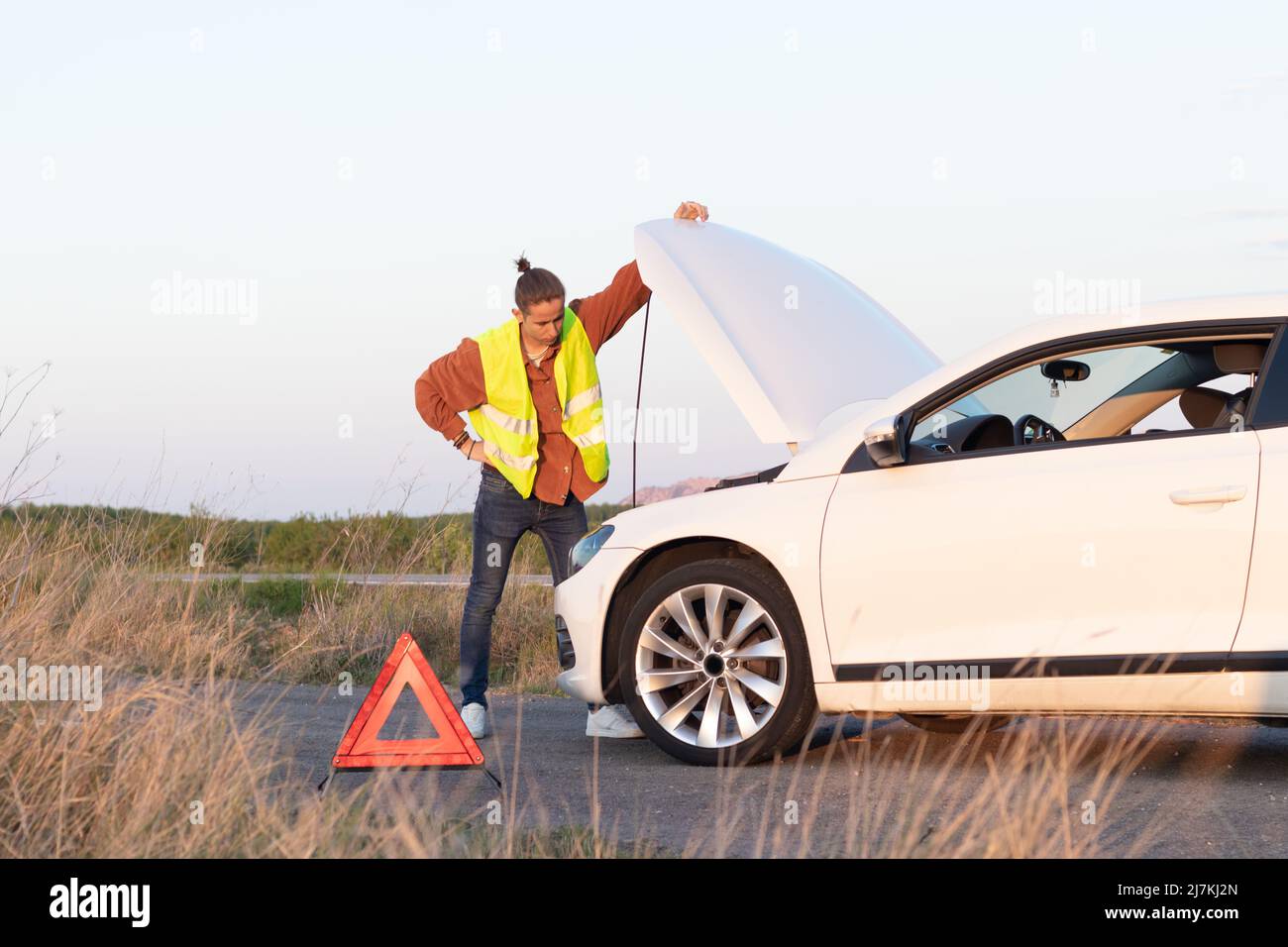 Angry man checking his broken car engine to fix it for going back home ...