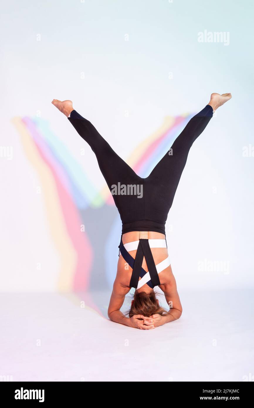 Full body back view of anonymous female practicing Salamba Shirshasana ...