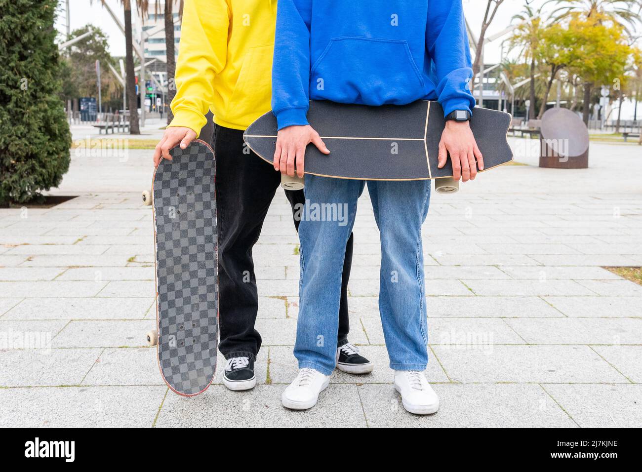 Crop view of two faceless friends skaters wearing blue and yellow ...