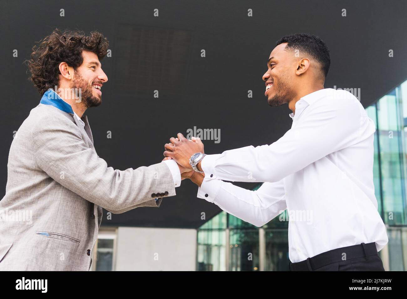 Side view of positive multiracial male coworkers looking at each other ...