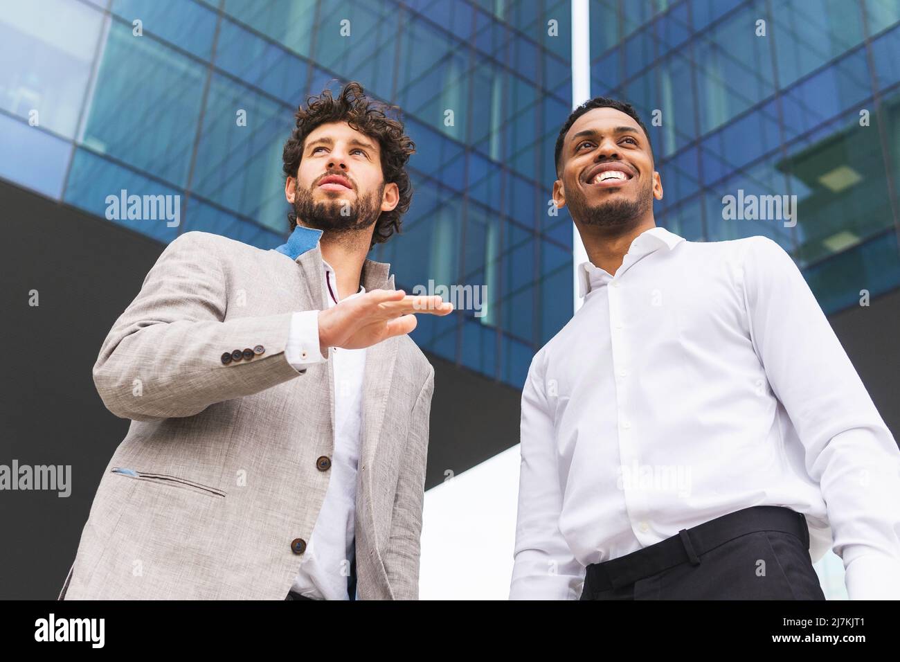 From below of cheerful multiracial coworkers in formal wear looking ...