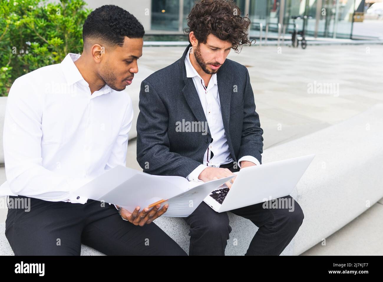 Multiracial male coworkers in formal wear with documents typing on ...