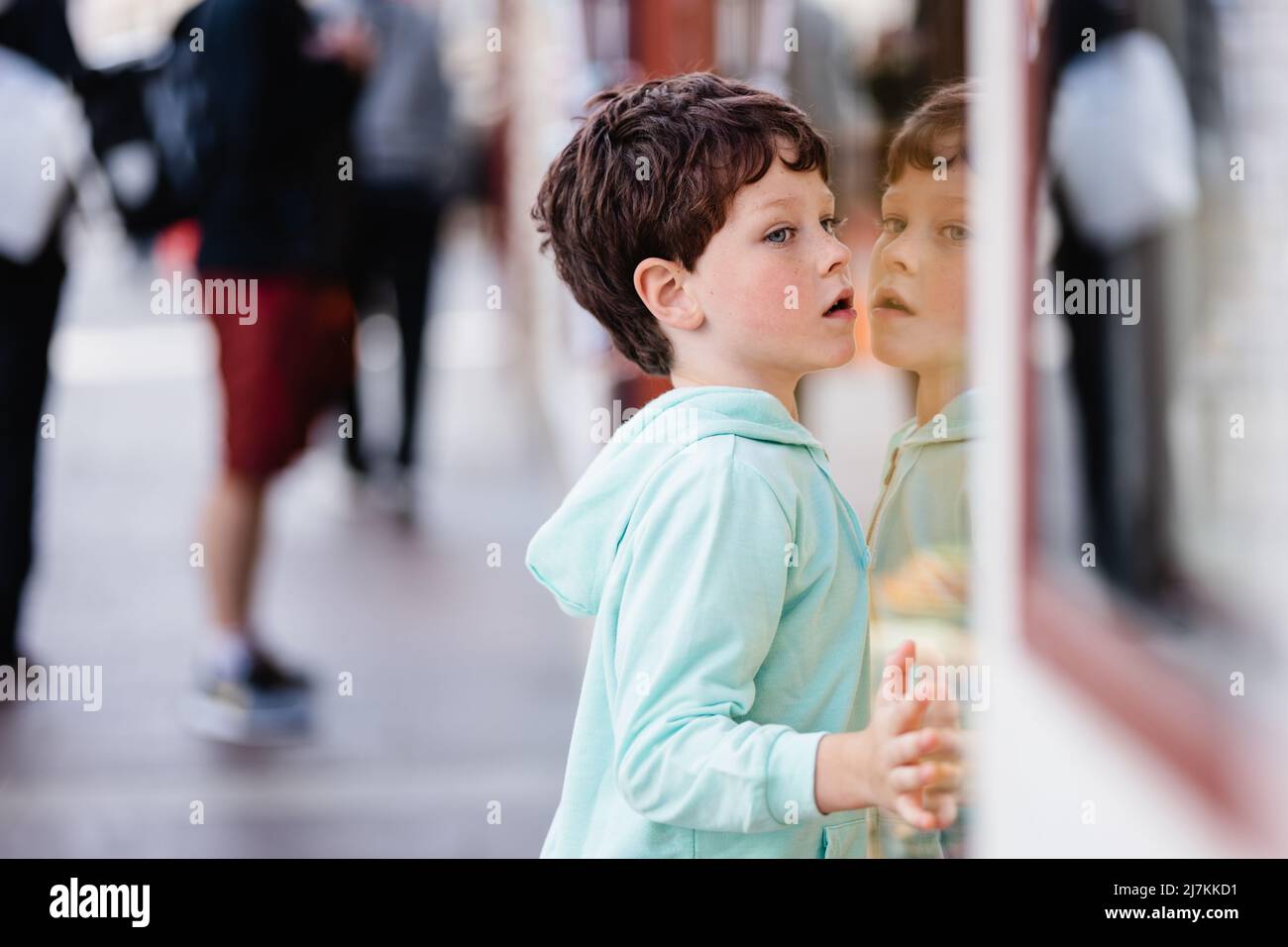 Side view of curious little boy in turquoise hoodie with dark hair ...