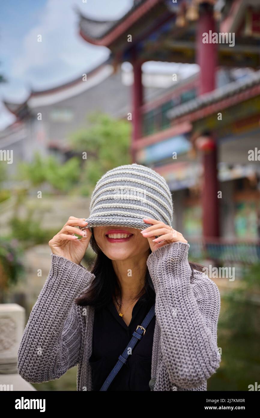 Portrait of happy Asian girl with beanie in Chinese traditional town ...