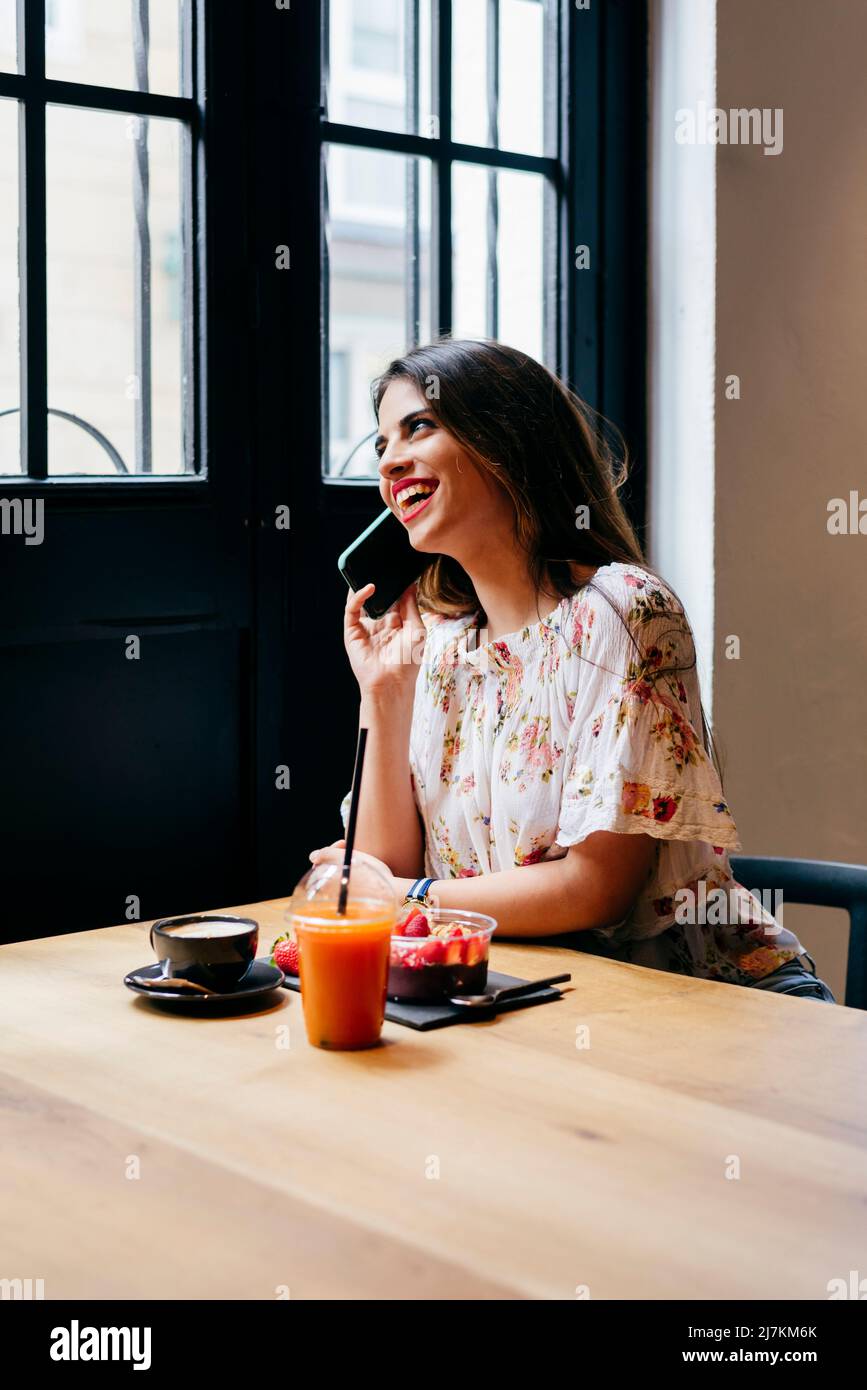 Beautiful modern female enjoying fruit juice and eating breakfast while ...