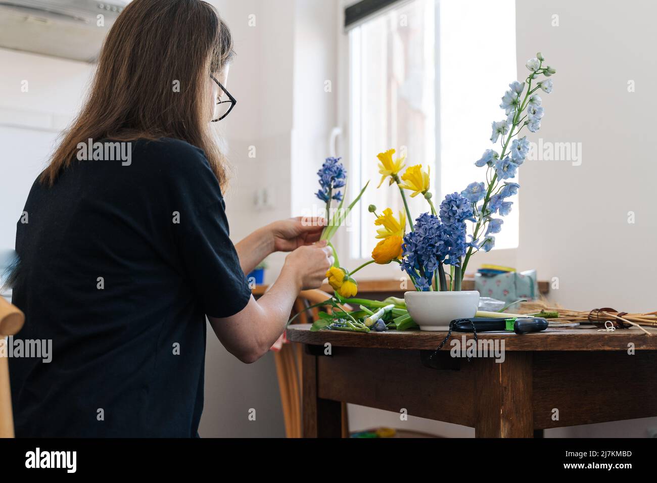 Side view of focus female florist at table doing Ikebana japanese art ...