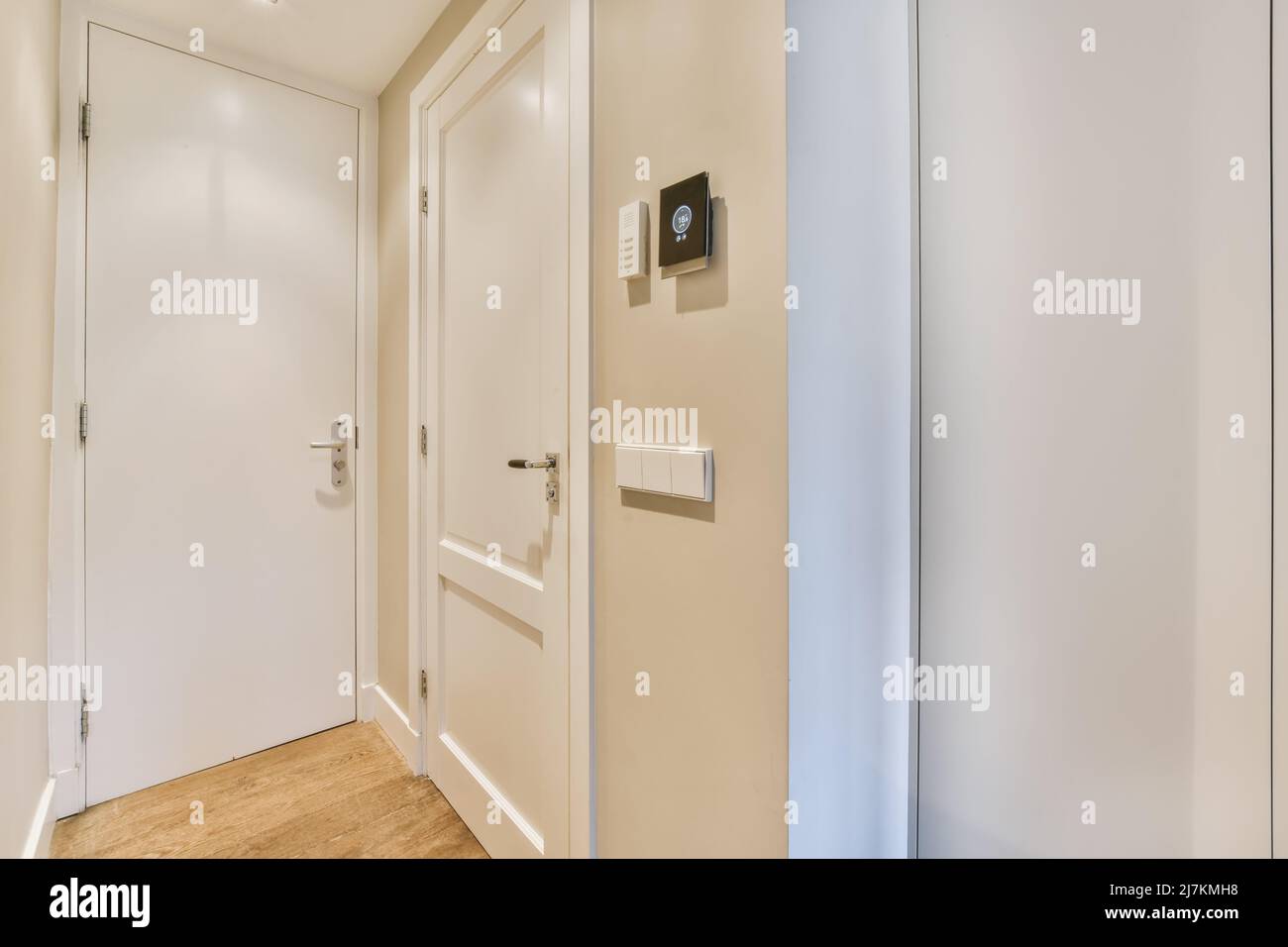Closed white room doors with stainless handles in light narrow hallway ...