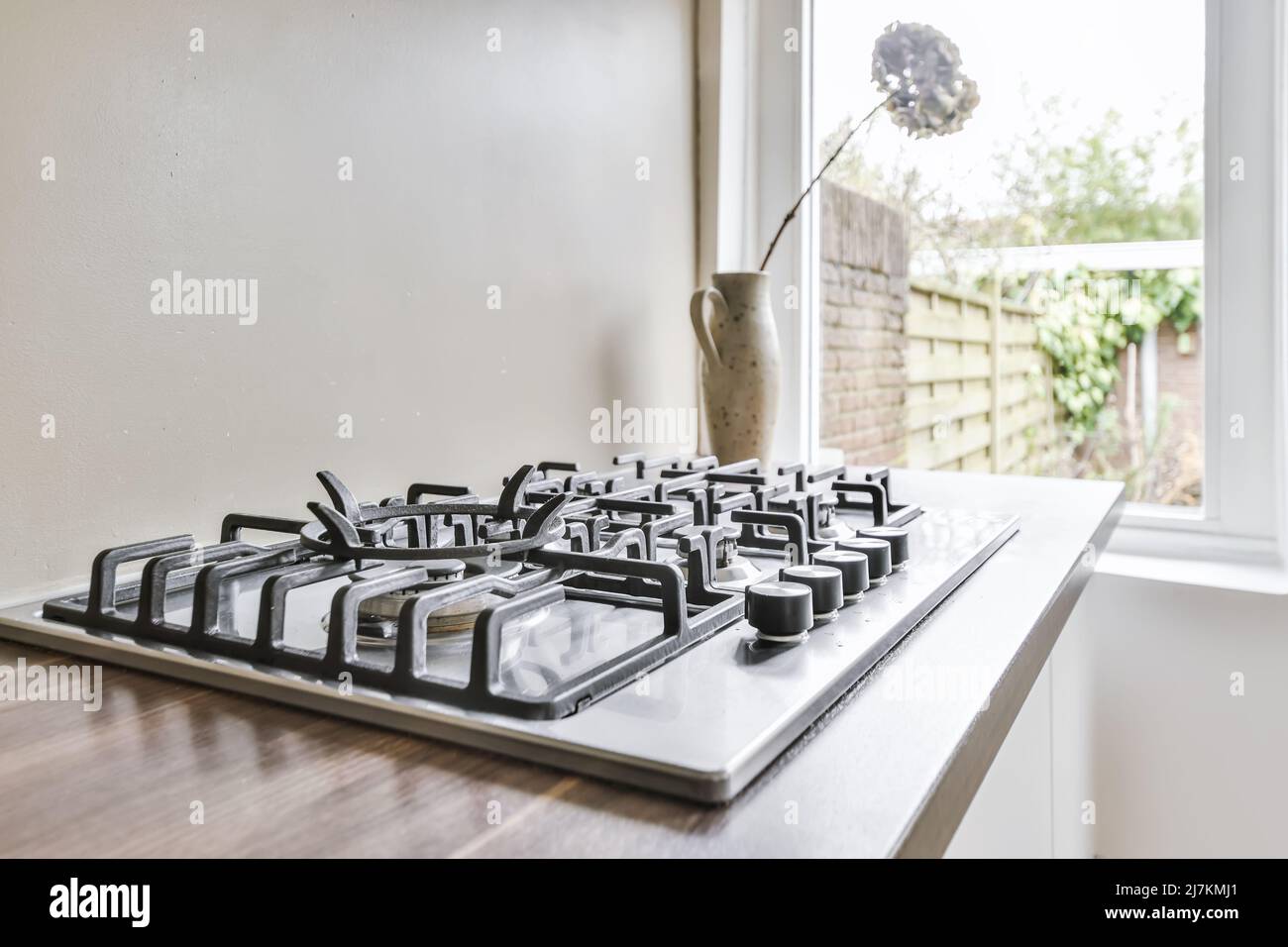 Gas cooker on wooden counter with flower in ceramic vase placed near ...