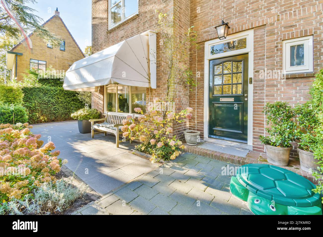Terrace of brick residential building with paved walkway and blooming ...
