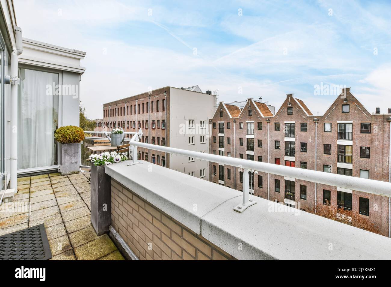 Terrace of modern building with metal railing and potted plants against ...