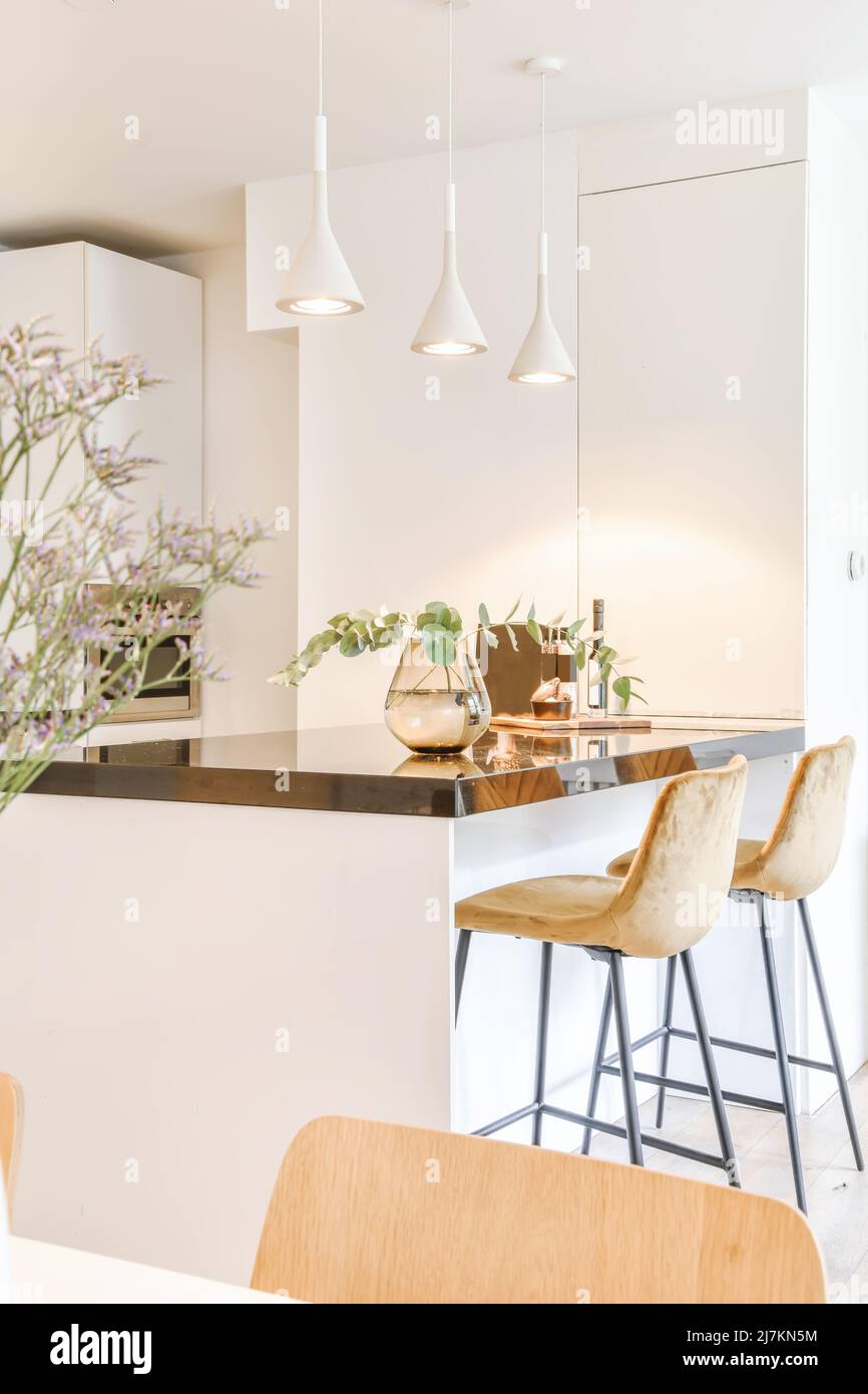 Comfortable chairs placed at counter in modern spacious open plan ...