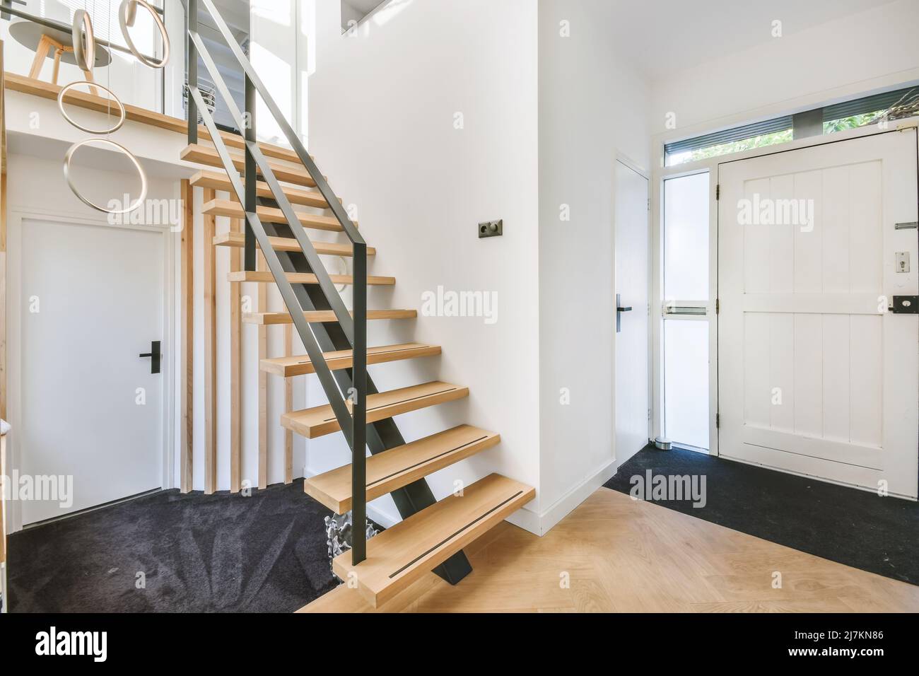 Stairway with wooden steps and black railing near wall in light ...