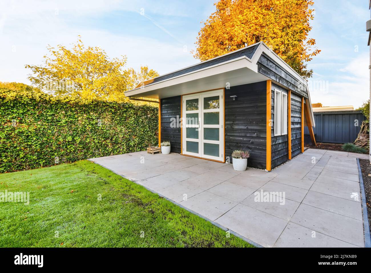 Cabin with doors located on tiled terrace near grassy lawn and green ...