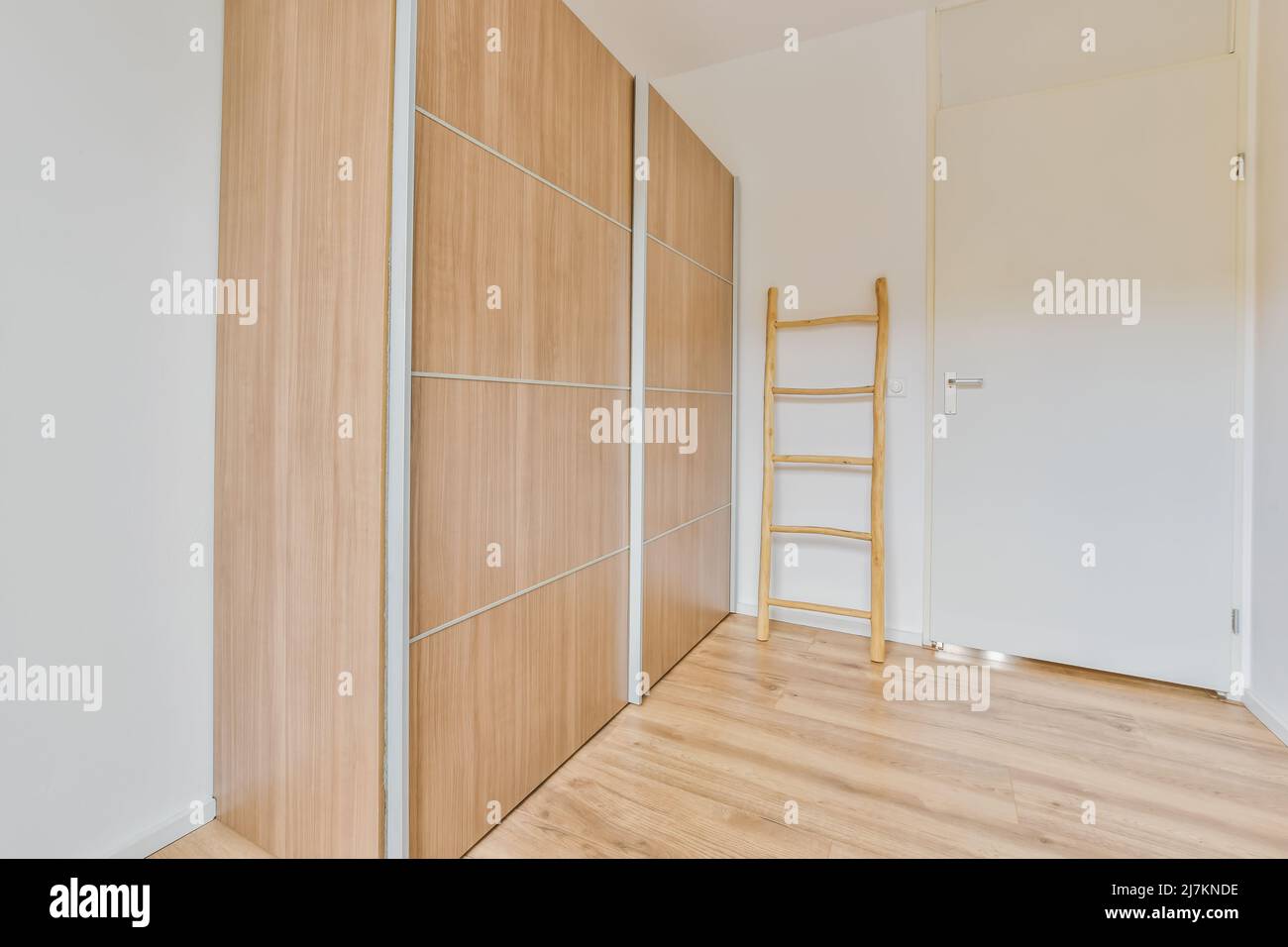 Ladder placed in light stylish room with wardrobe and glass door in ...