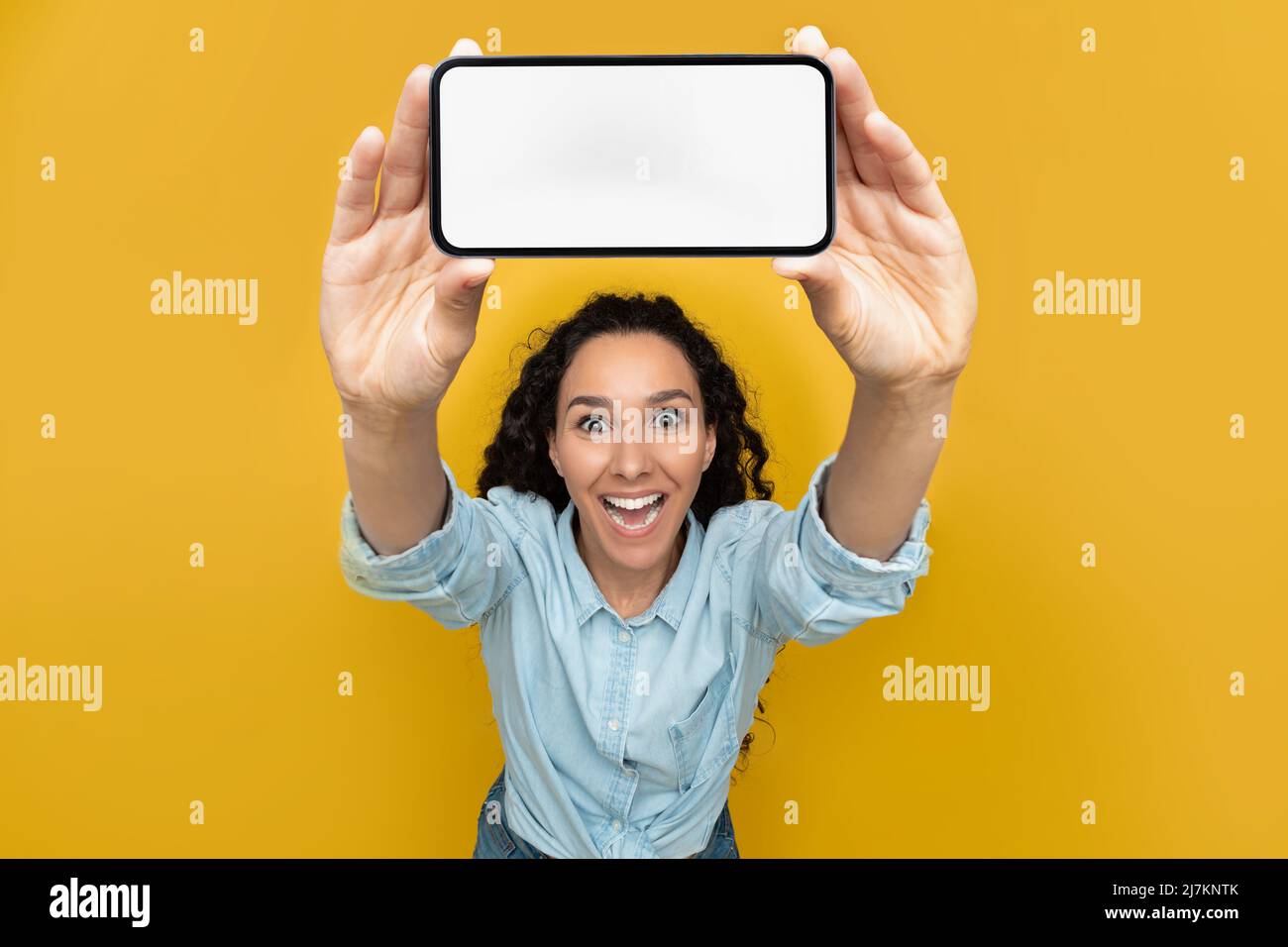 Excited lady showing blank mobile phone screen at studio Stock Photo ...