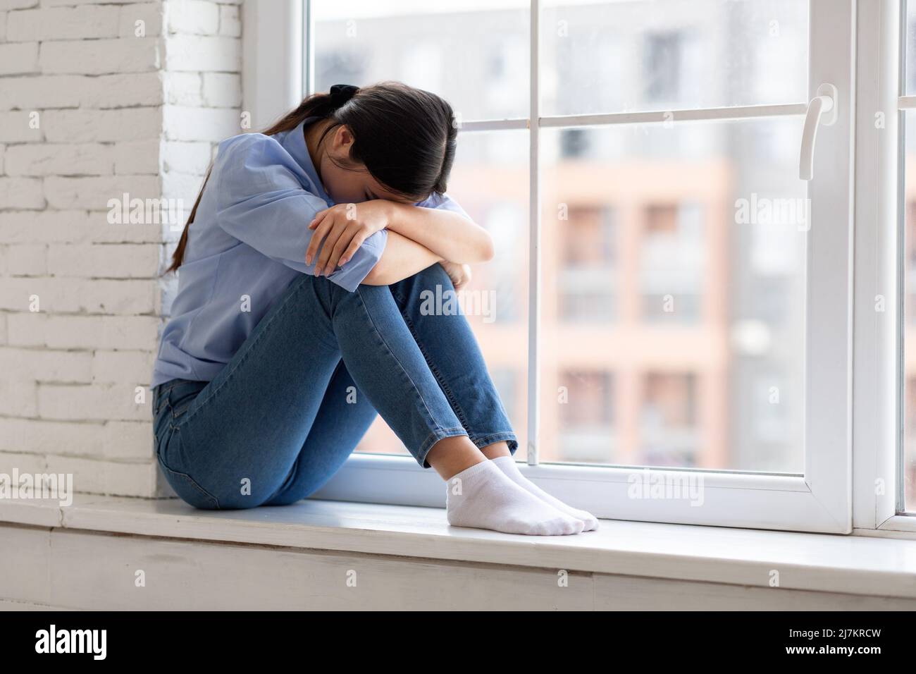 Side view of asian woman sitting on window, crying Stock Photo - Alamy
