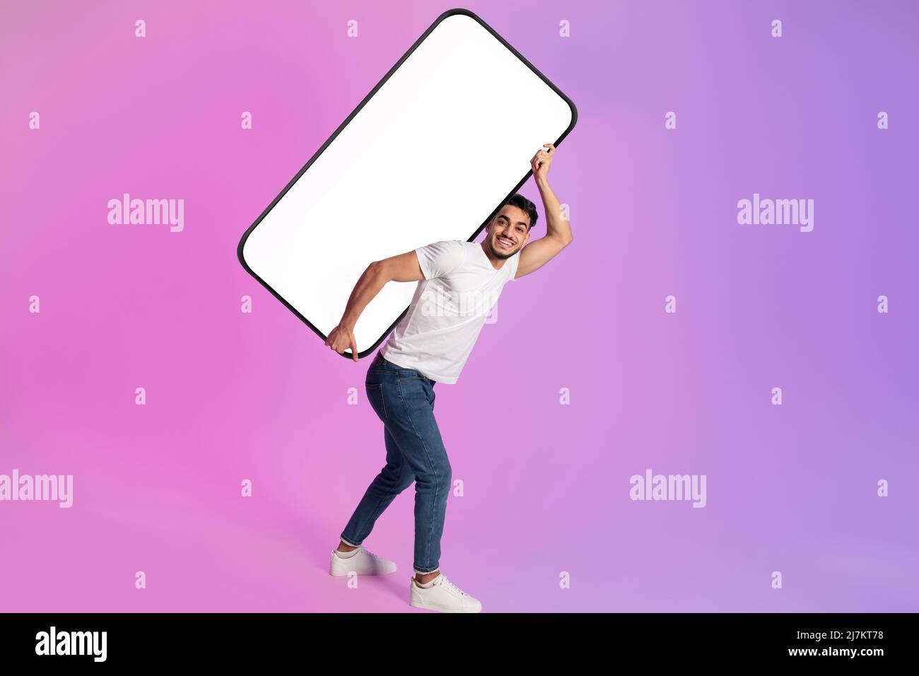 Full length portrait of cheery young Arab man carrying huge heavy ...