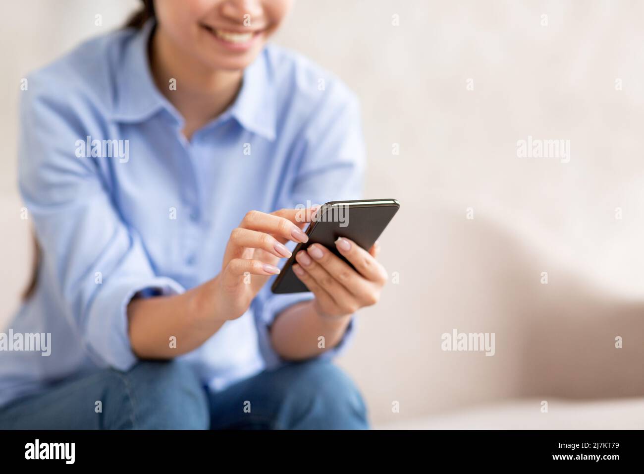 Unrecognizable lady sitting on sofa, using cell phone, cropped Stock ...