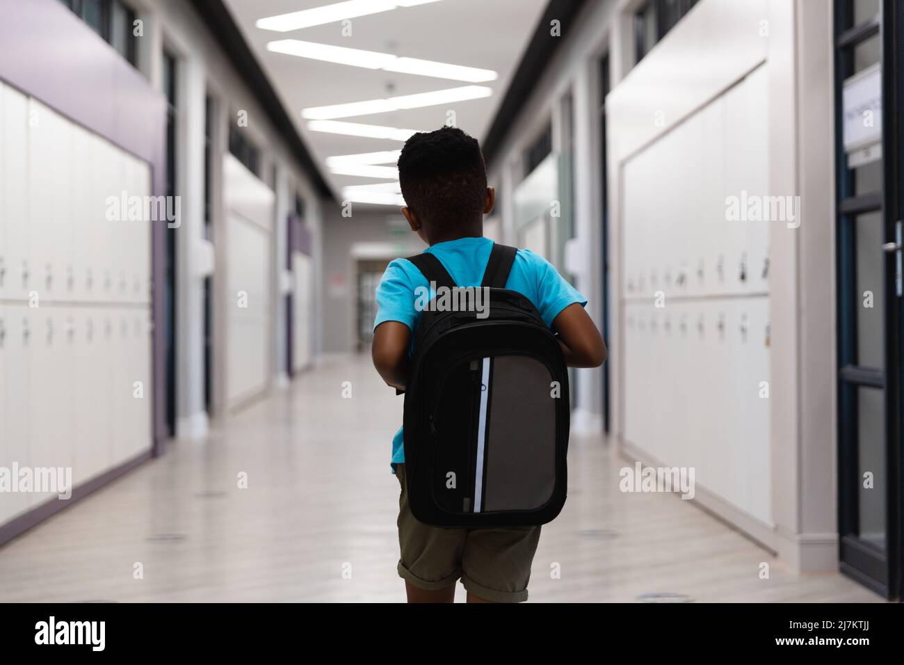 Rear view of african american elementary schoolboy with backpack ...