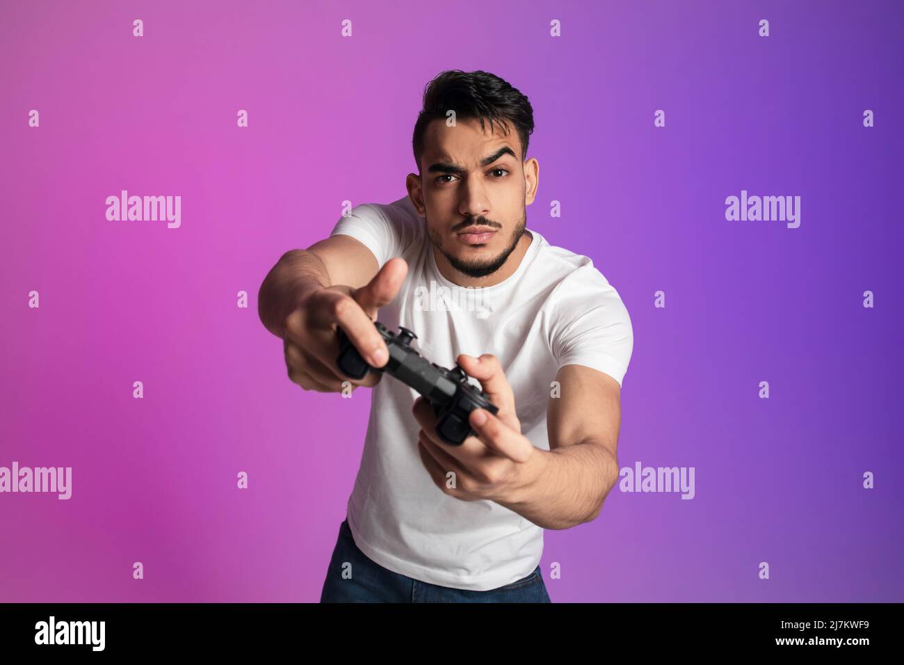 Focused young Arab guy playing video game with joystick, participating ...