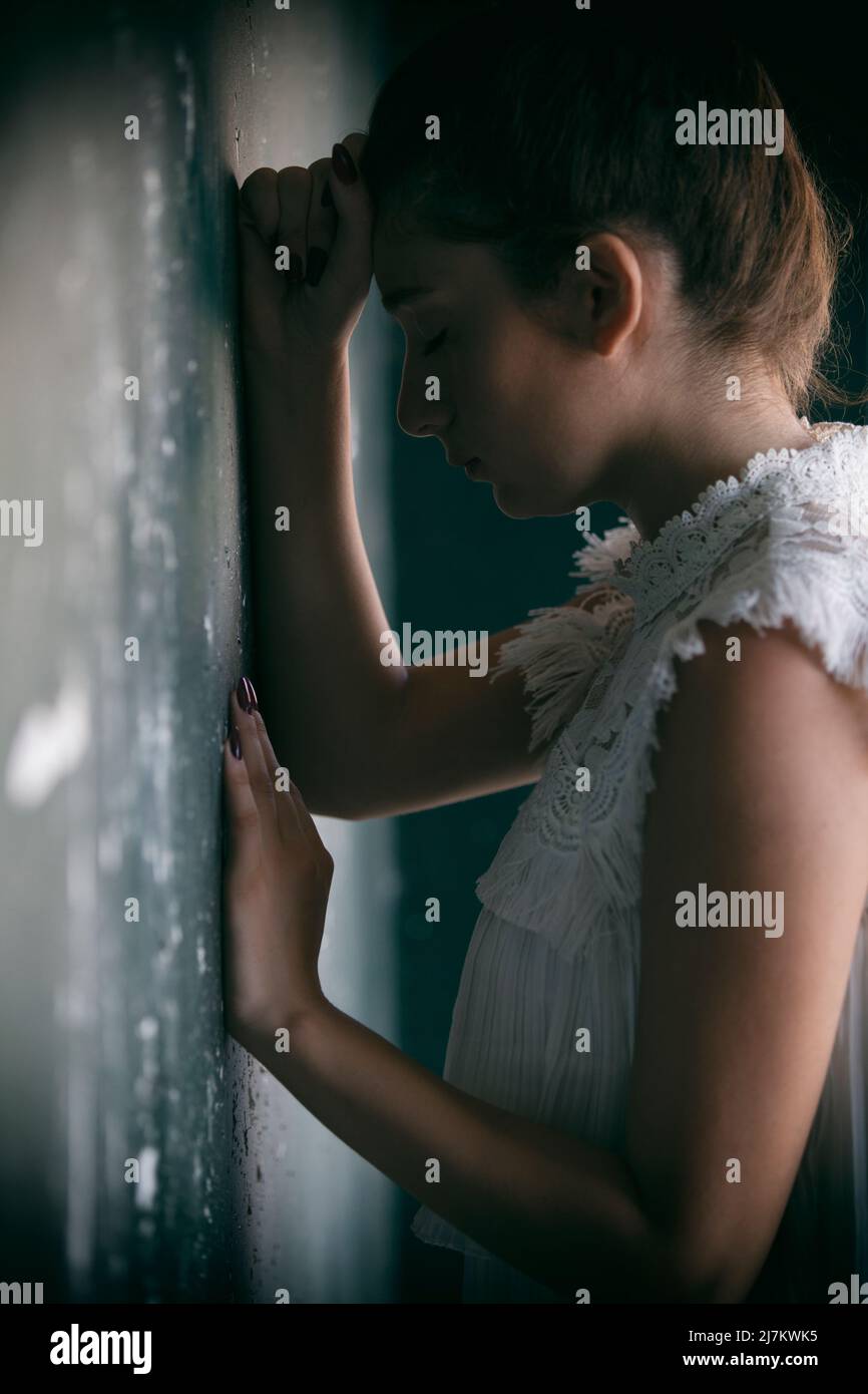 Miserable woamn leaning against the wall Stock Photo - Alamy