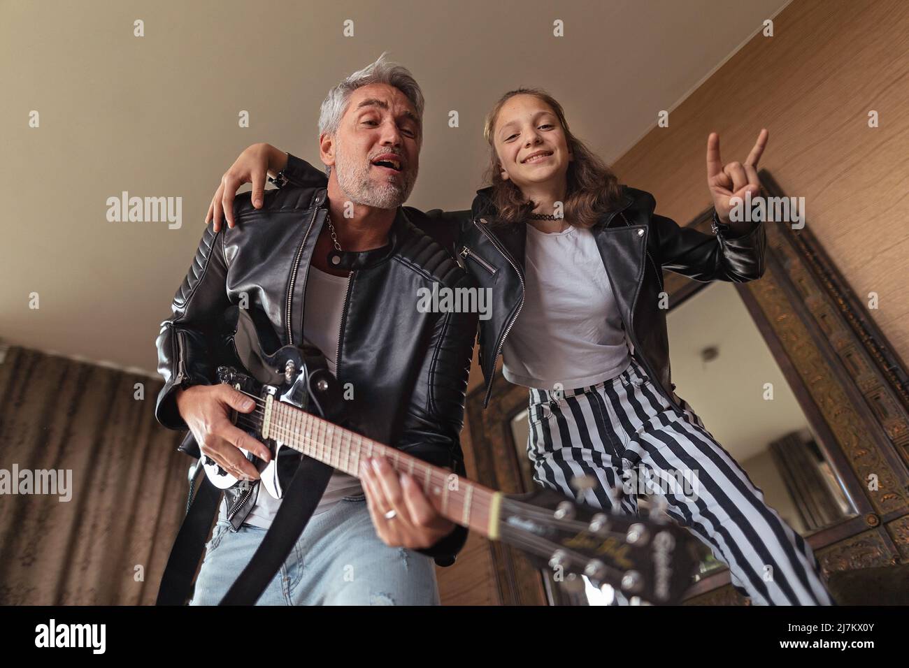 Father rock guitarist having fun and and dancing with his teenage ...