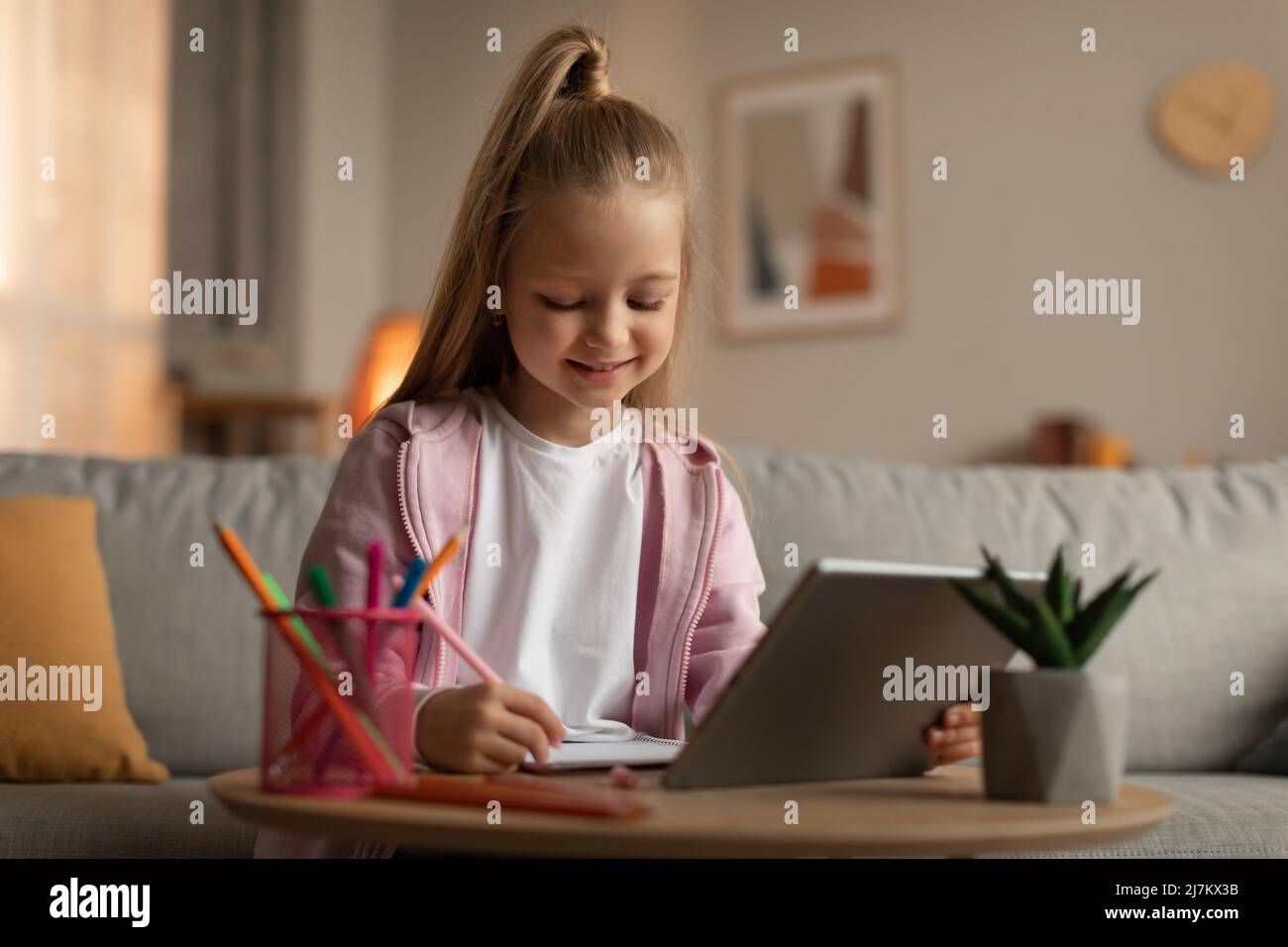 Little Girl Learning Using Tablet And Taking Notes At Home Stock Photo ...