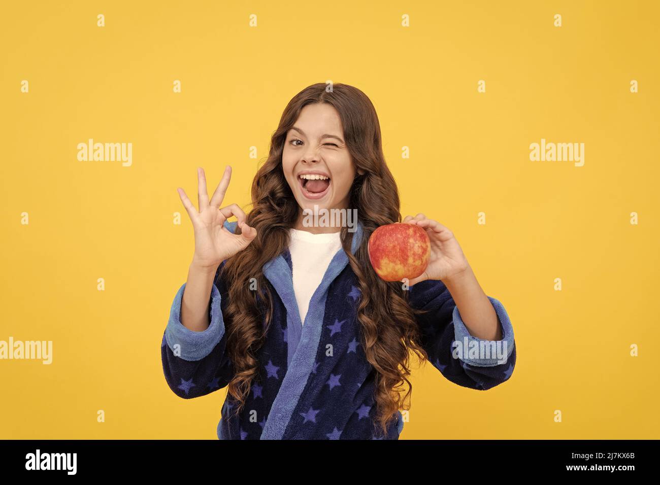 cheerful teen girl with curly hair in comfortable pajama going to eat ...