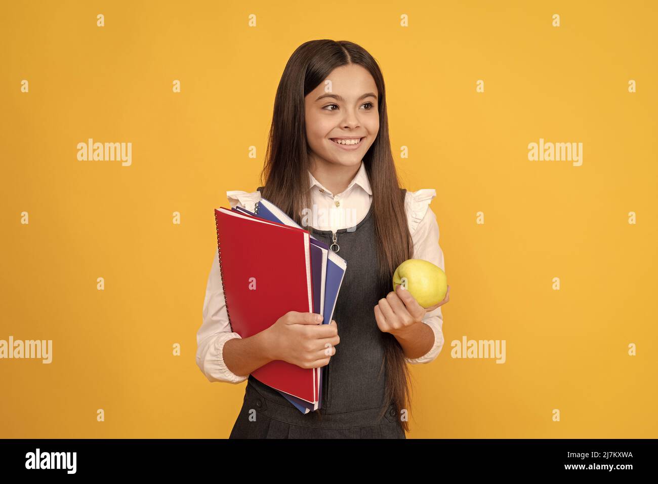 Happy girl child back to school holding apple and books yellow ...