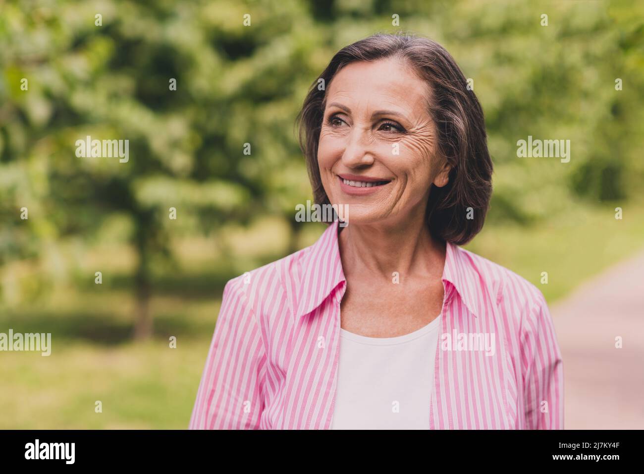 Photo of sweet dreamy retired woman dressed striped shirt walking ...
