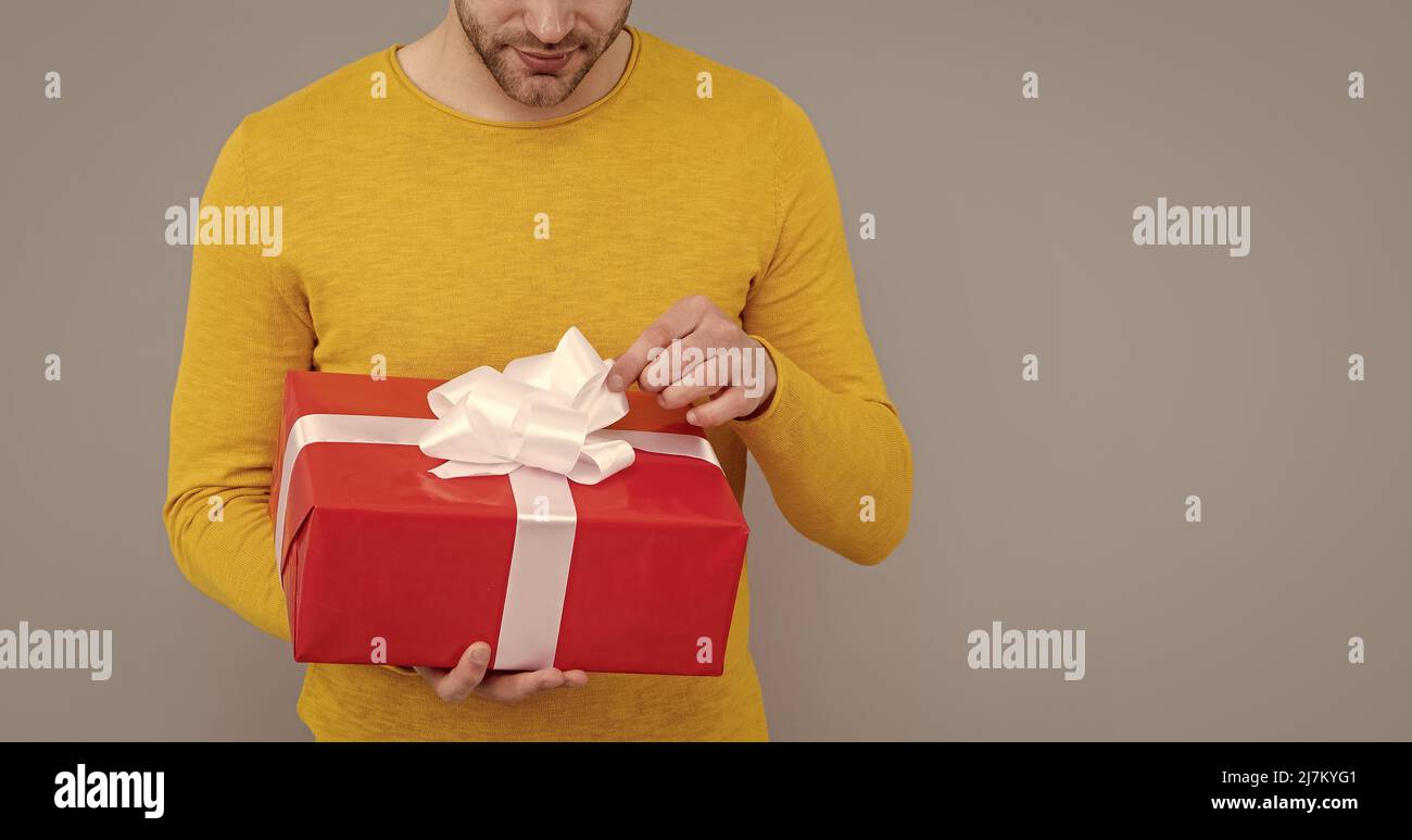 Unshaven man cropped view untie bow on present box grey background copy ...
