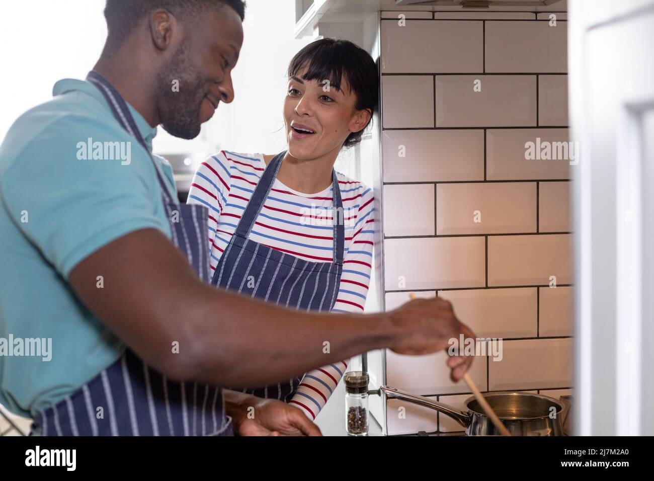Happy multiracial young couple cooking food together at home Stock ...