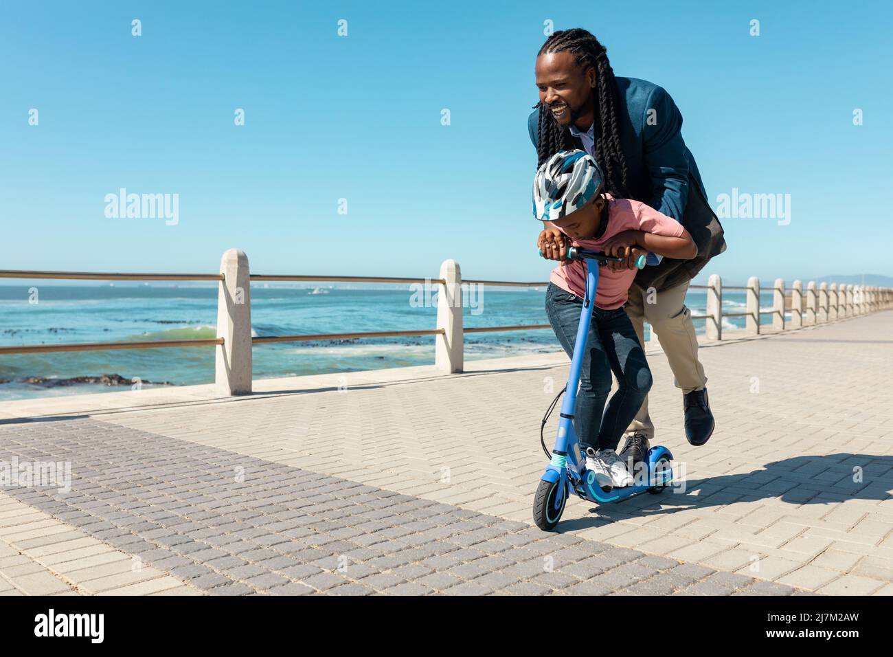 Full length of happy african american father and son riding push ...