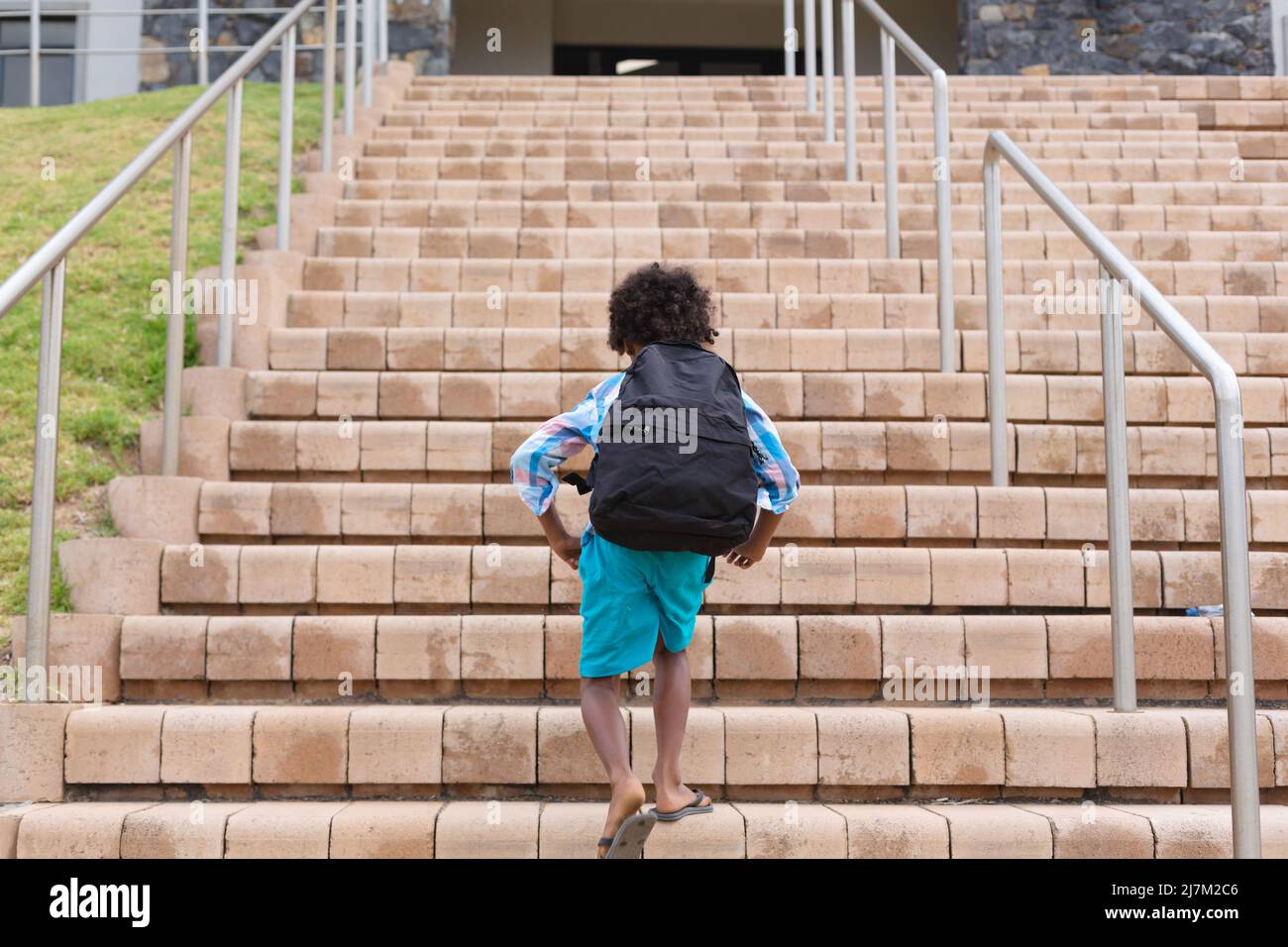 Rear view of african american elementary schoolboy with backpack ...