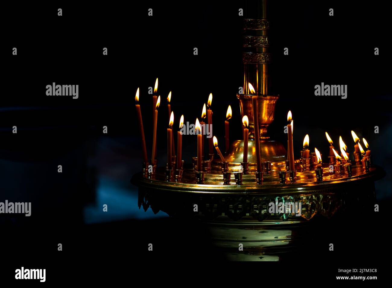 Candlestick with many burning candles in the dark interior of the ...