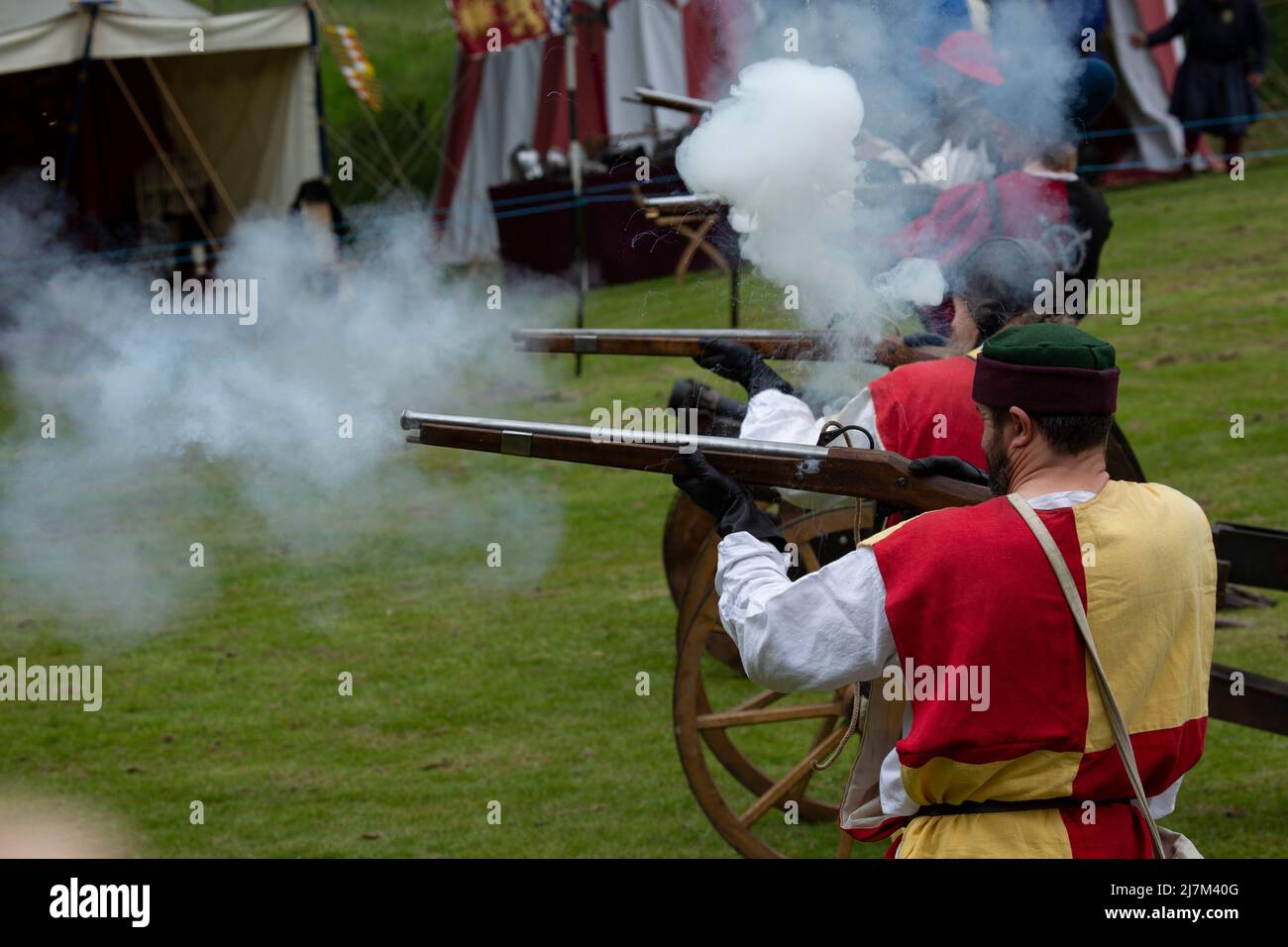 men and women firing muskets and wooden cannons during a re enactment ...