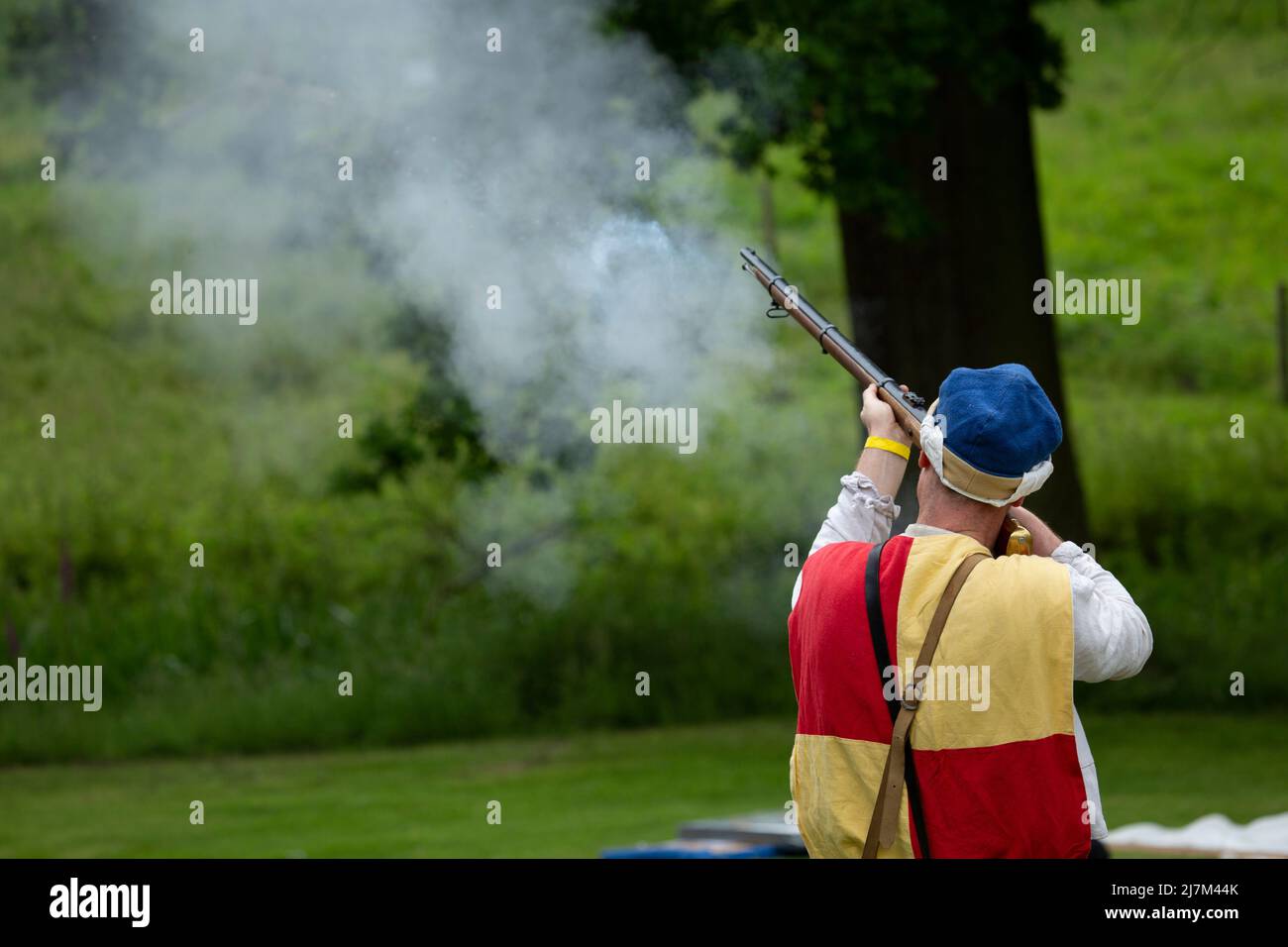 men and women firing muskets and wooden cannons during a re enactment ...