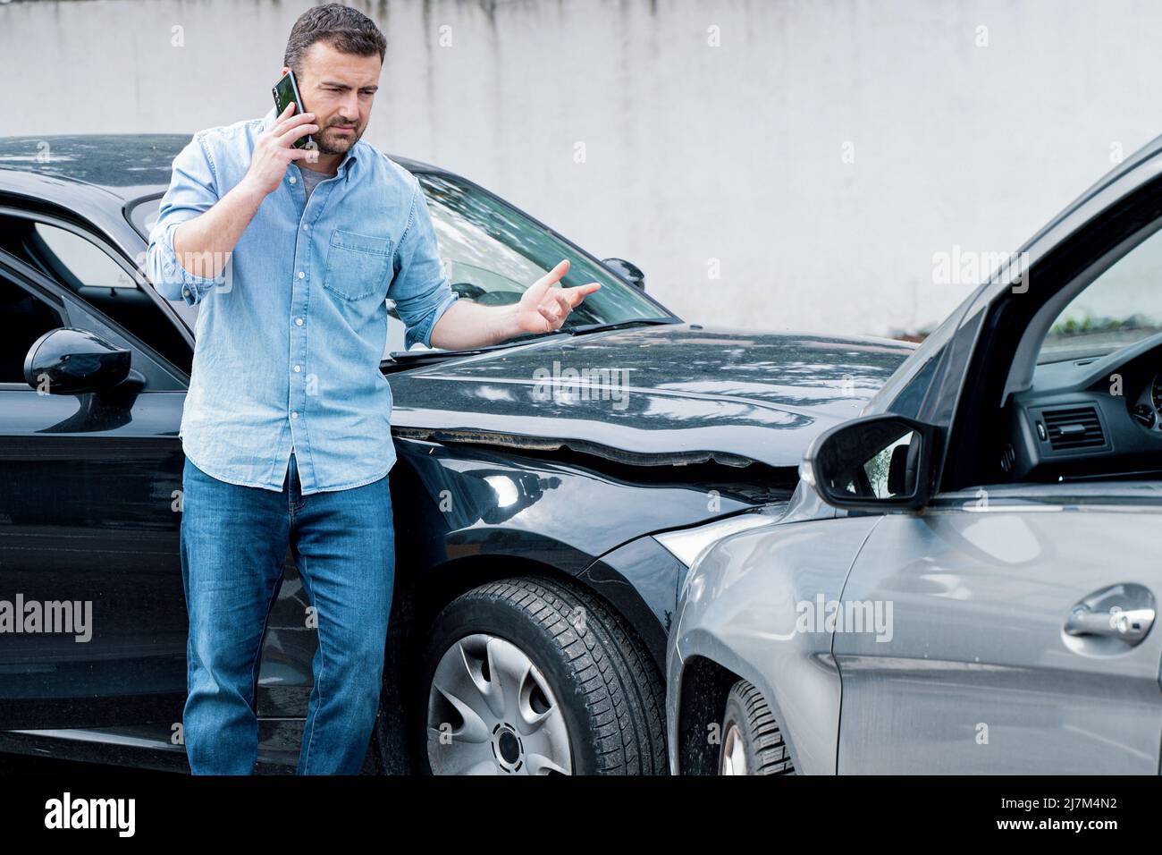 One man reporting car crash damage calling insurance roadside service ...