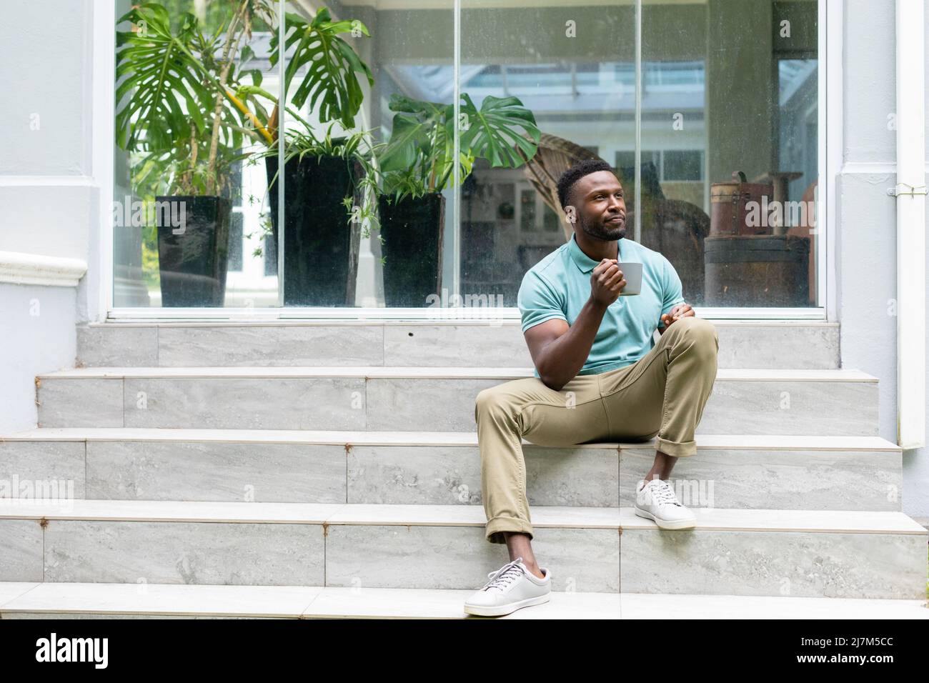 Thoughtful african american young man having coffee while sitting on ...
