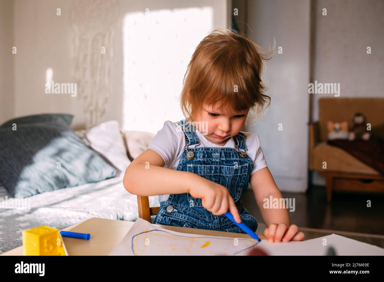 Small child at home at the children's table draws with felt-tip pens ...