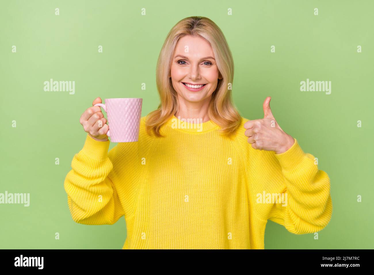 Photo of aged lady hold caffeine beverage mug make thumb up symbol rate ...