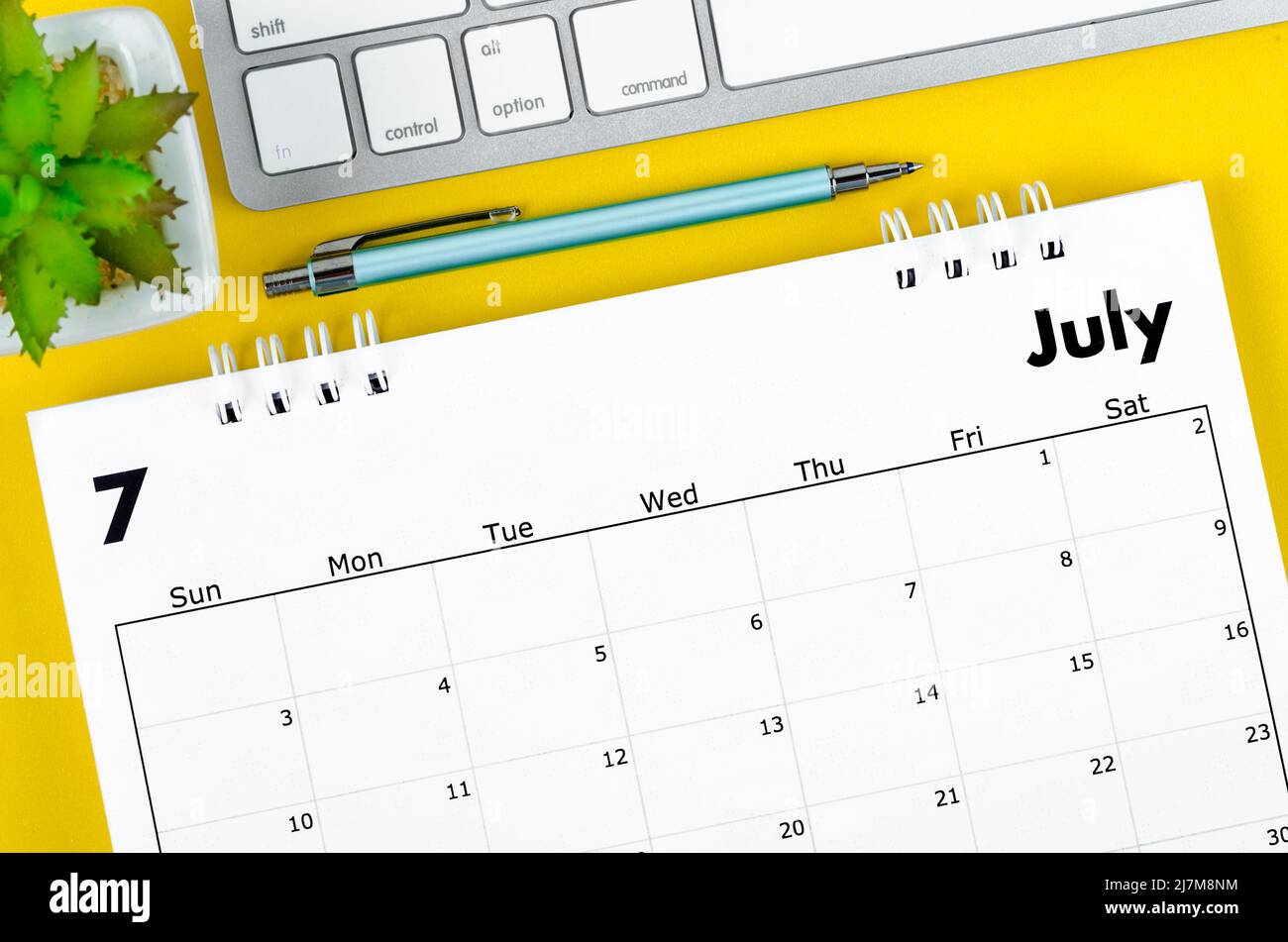 The July 2022 desk calendar with pen and keyboard computer on yellow ...