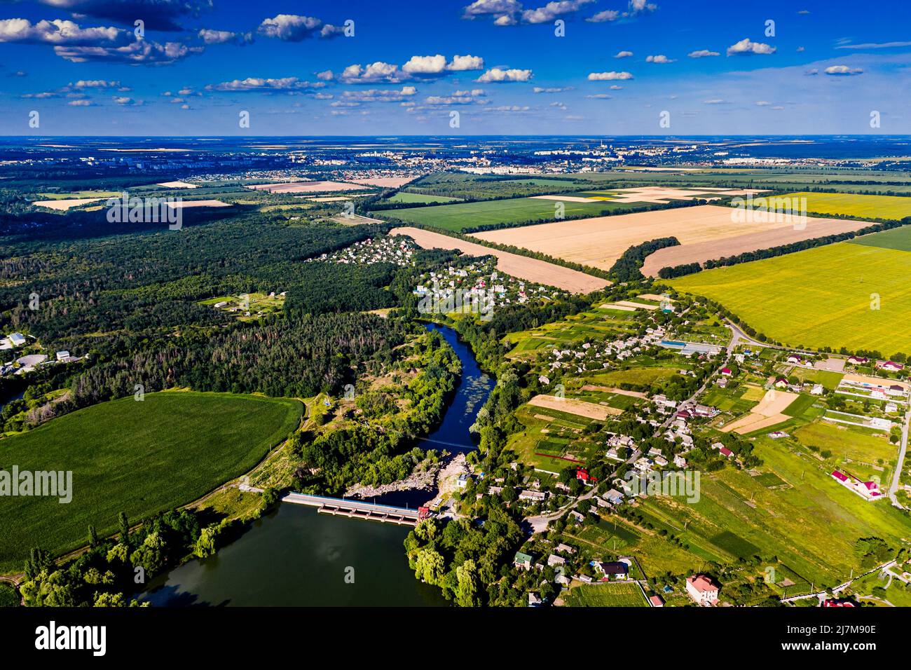 Top view of the dam, bridge over the river. Top view of green fields. Beautiful forest, blue sky ...