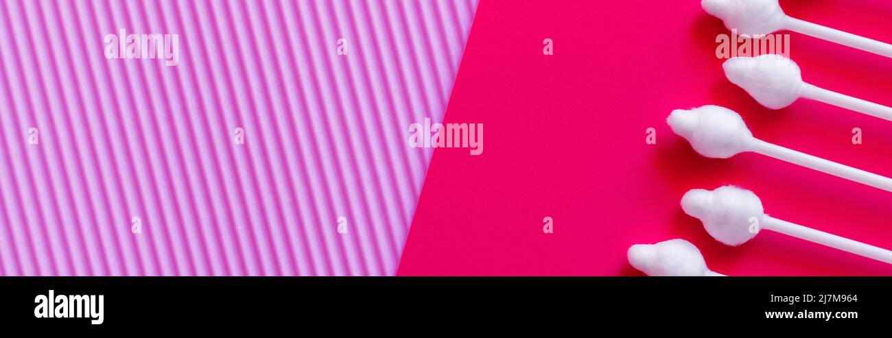 top view of cotton swabs on textured violet and pink background, banner ...