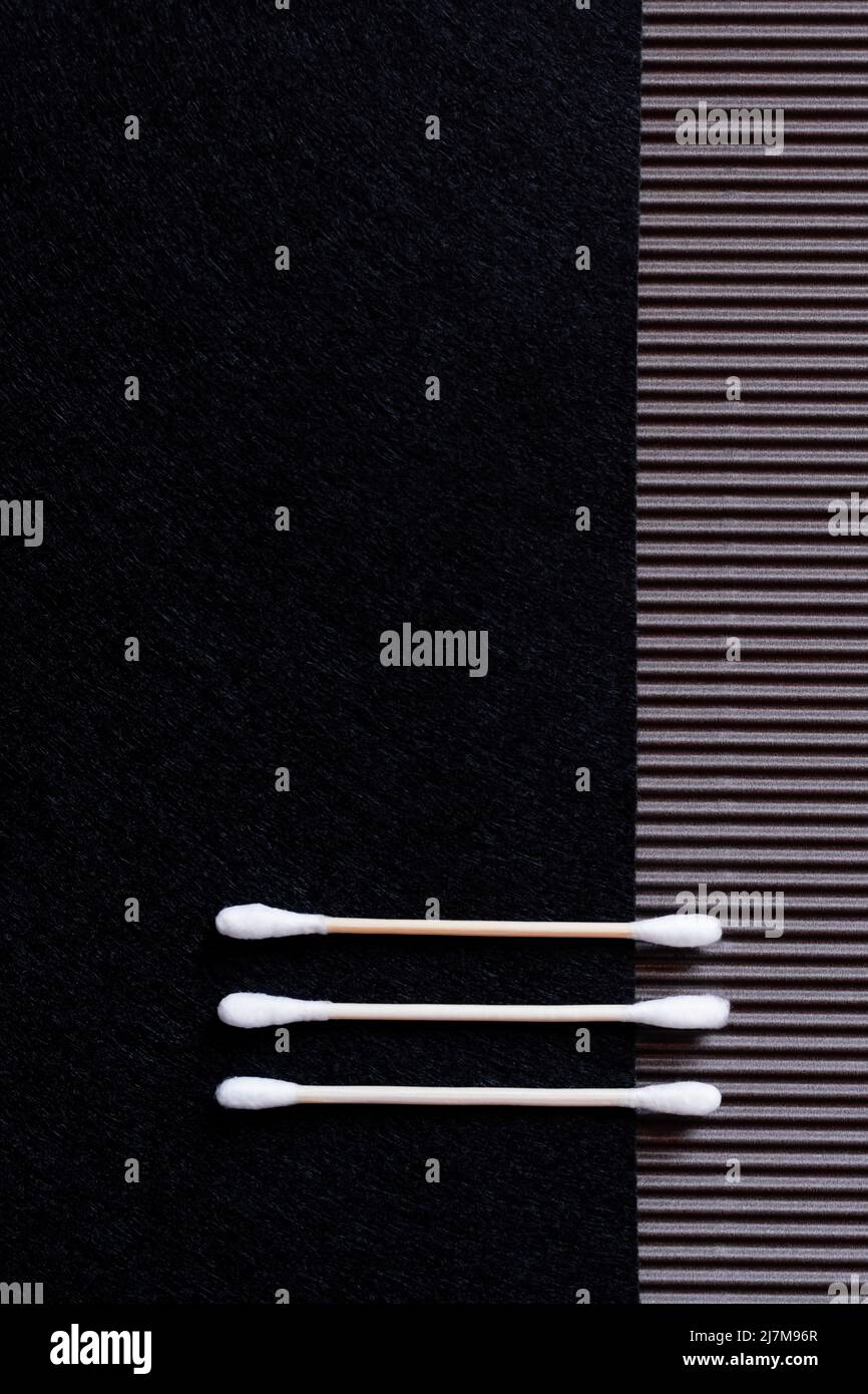 top view of two cotton ear sticks on black and textured background with ...