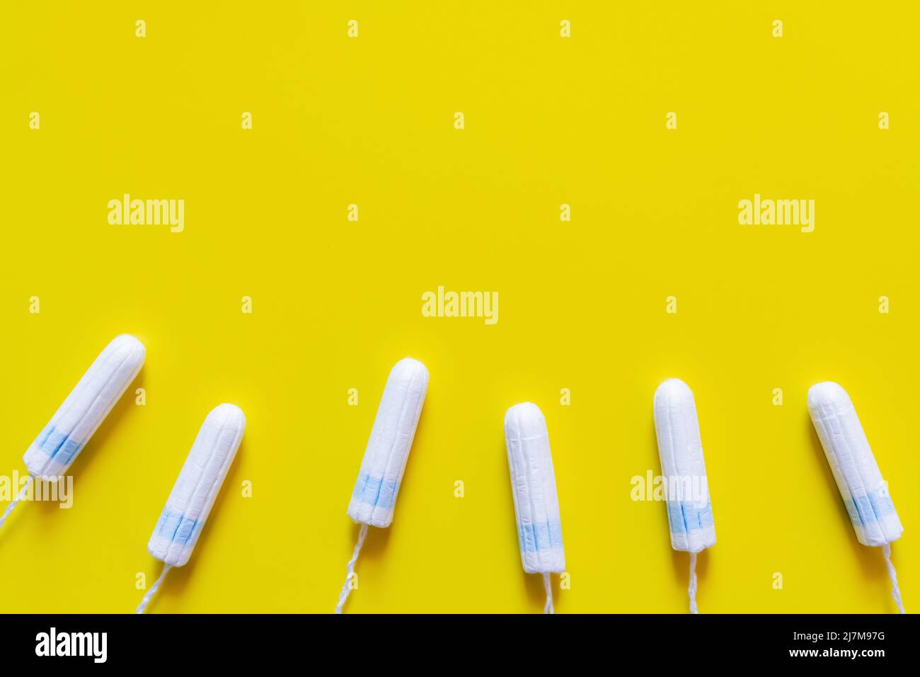 top view of white cotton tampons on yellow background with copy space ...