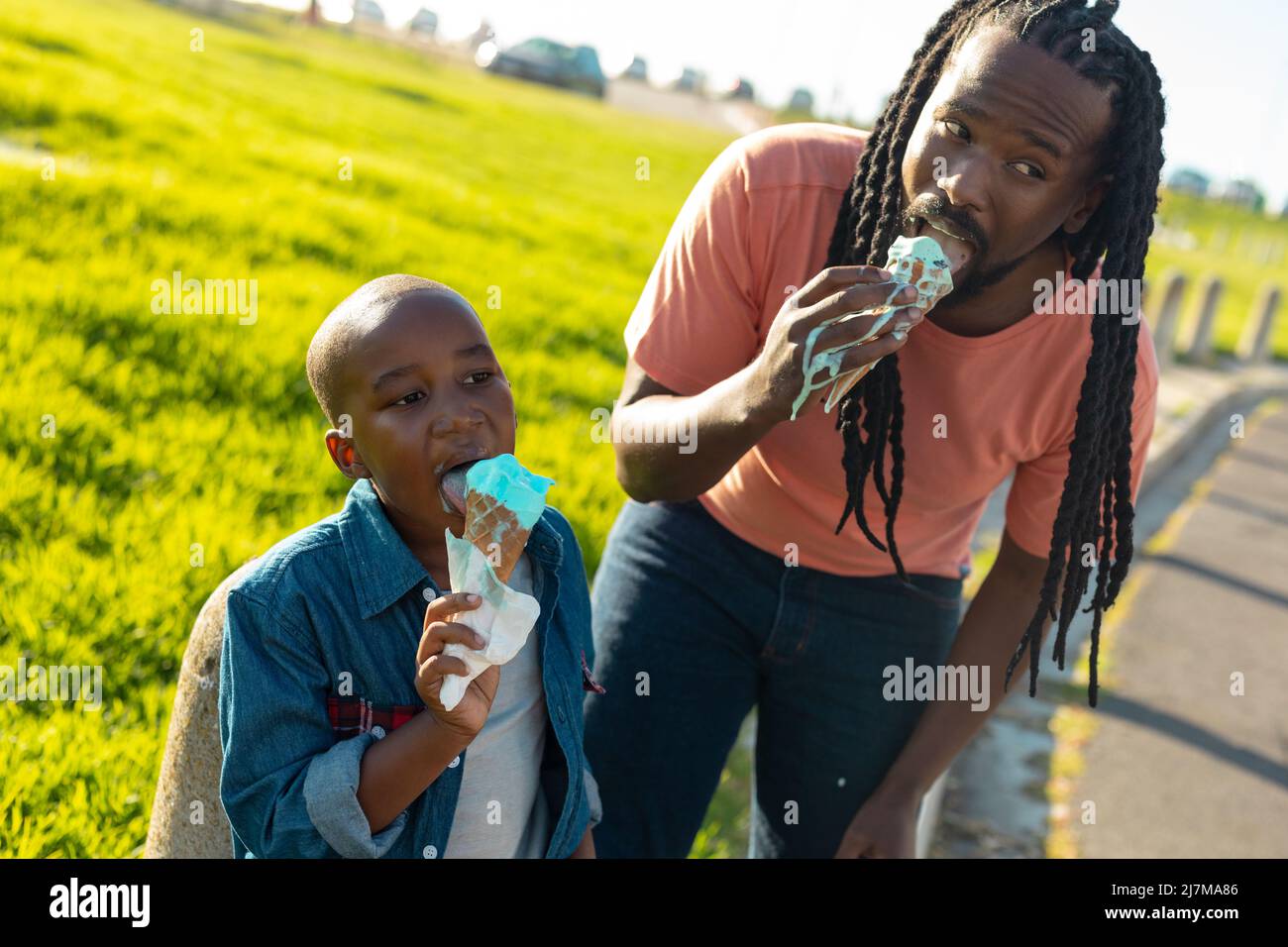 African american father and son eating melting ice cream on sunny day ...